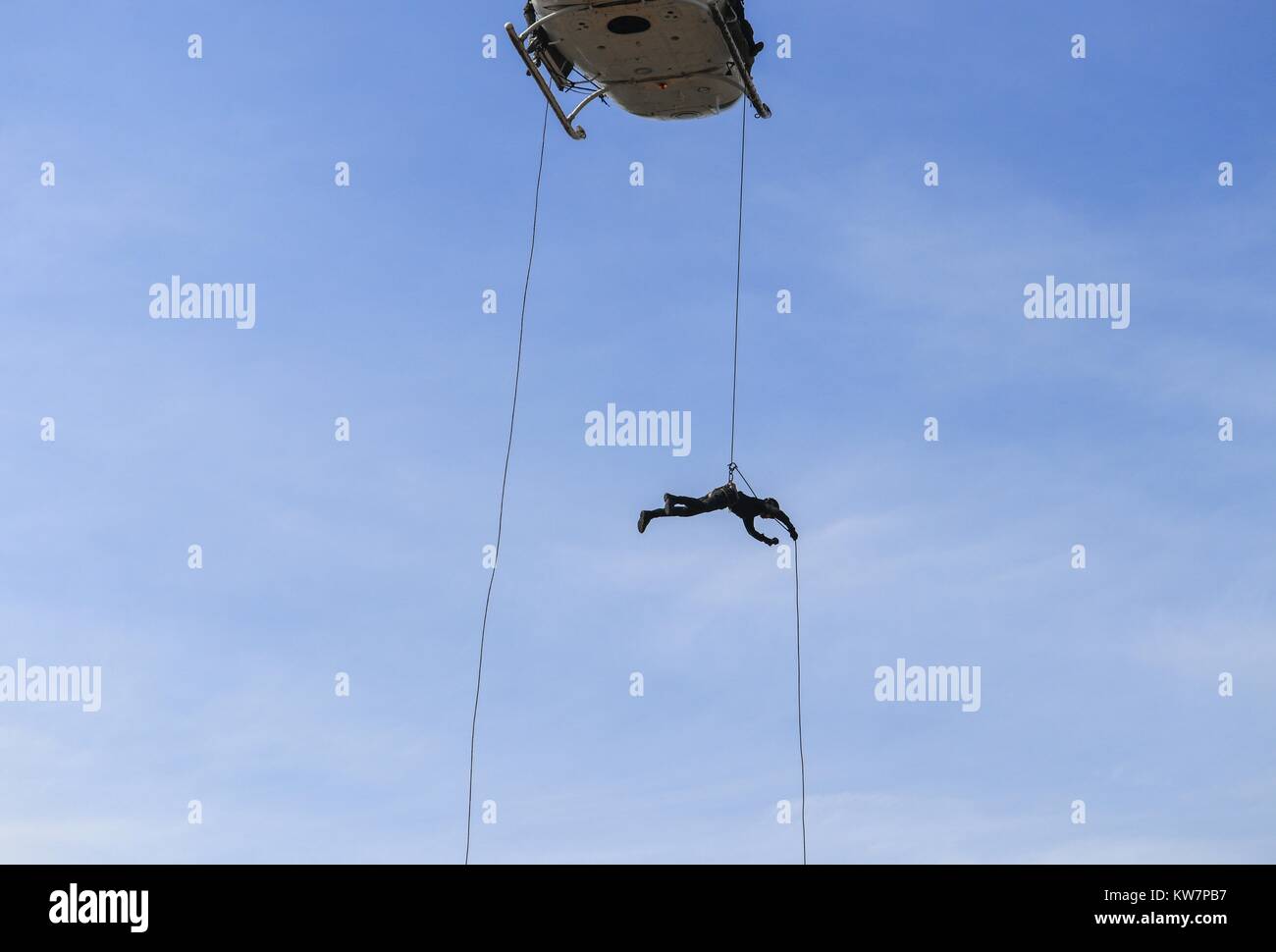 Soldier rappelling from helicopter in blue sky Stock Photo - Alamy