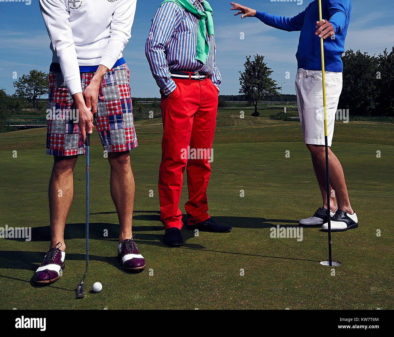Three golf players on green field Stock Photo - Alamy