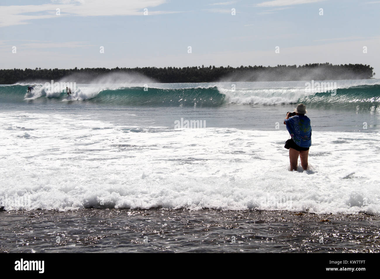 Photographer and serfers on wave near Pantai Sorake beach, Indonesia ...