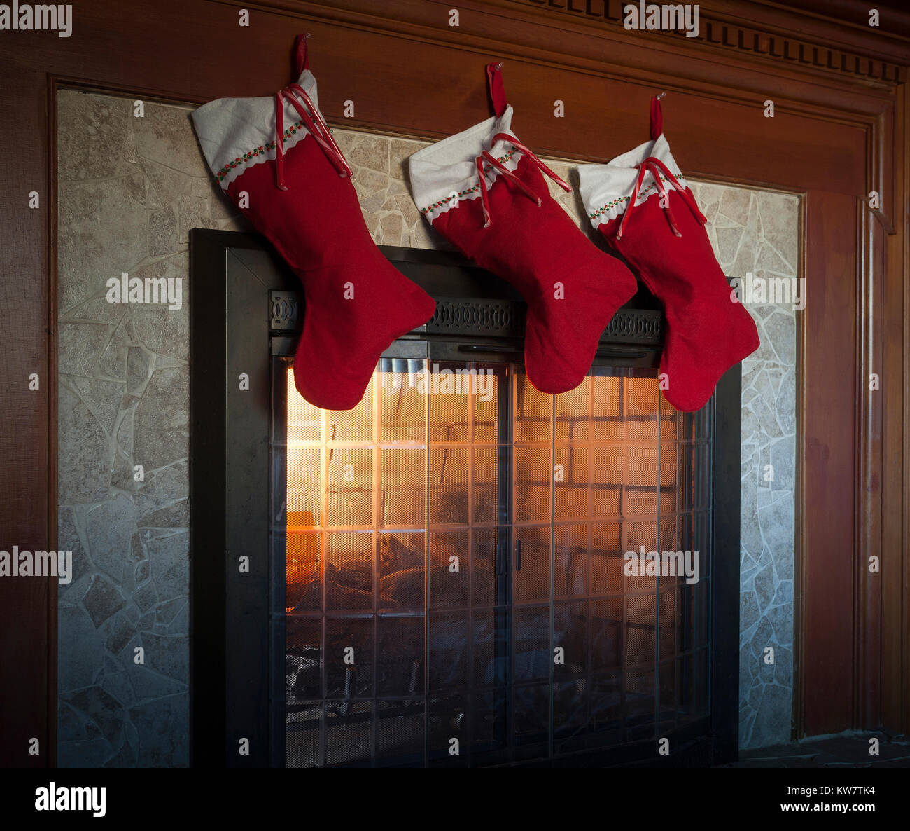Three stockings hung on a fireplace with candy canes on their sides ...