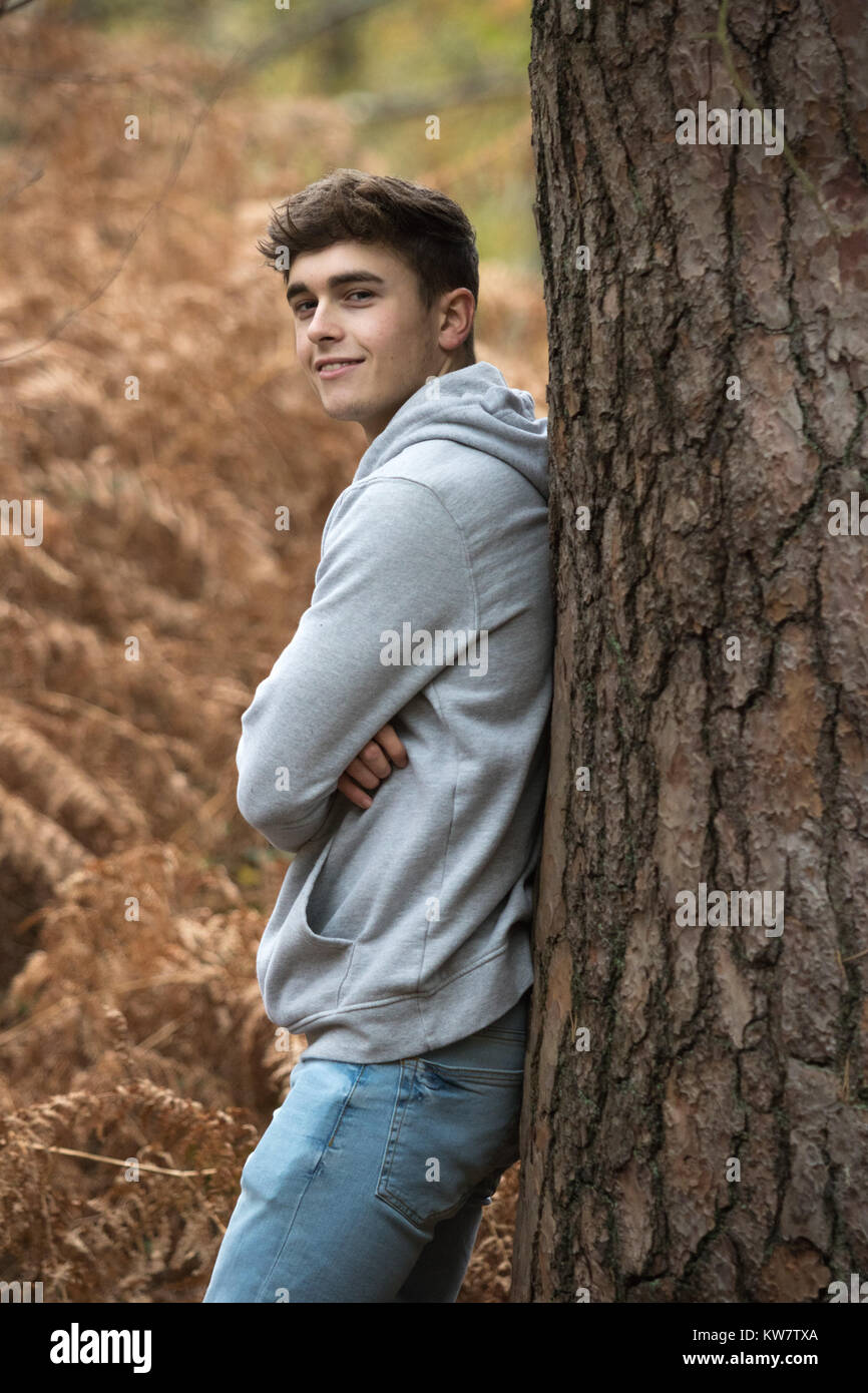 Boy leaning against tree hi-res stock photography and images - Alamy