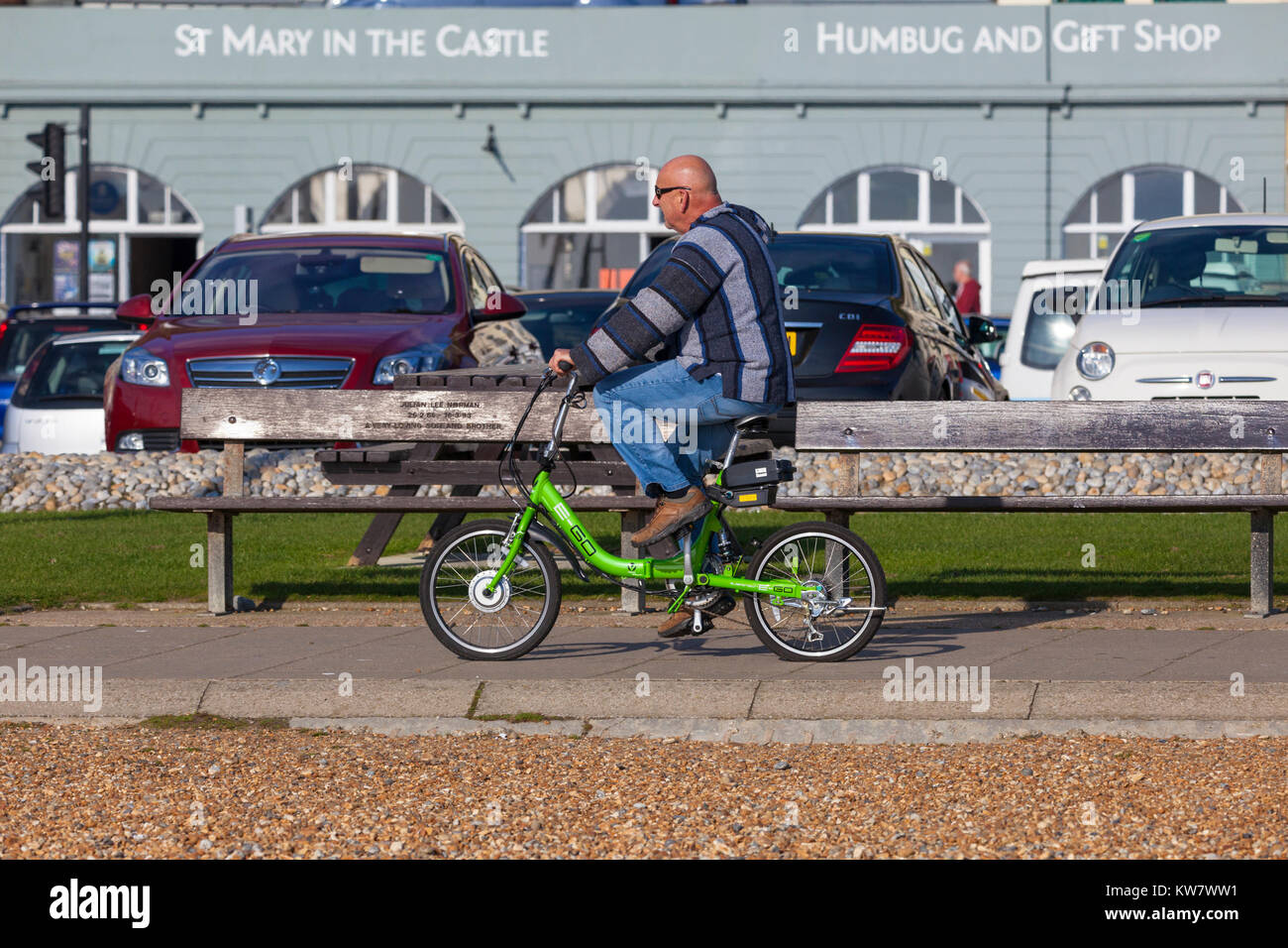 A bald man rides by on his green coloured bike with St mary in the ...