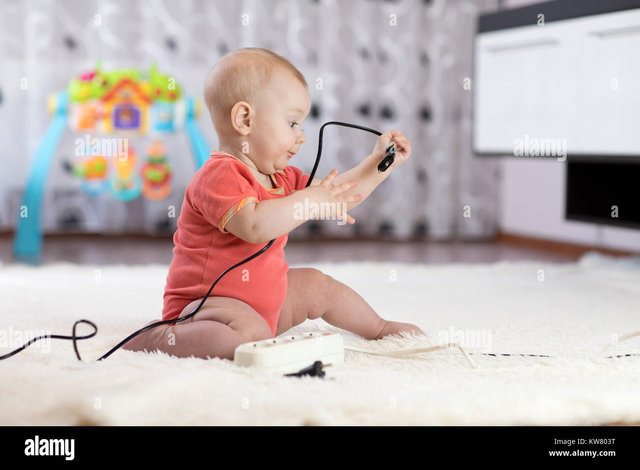 8 months old age baby pulling cables from electrical extension Stock ...