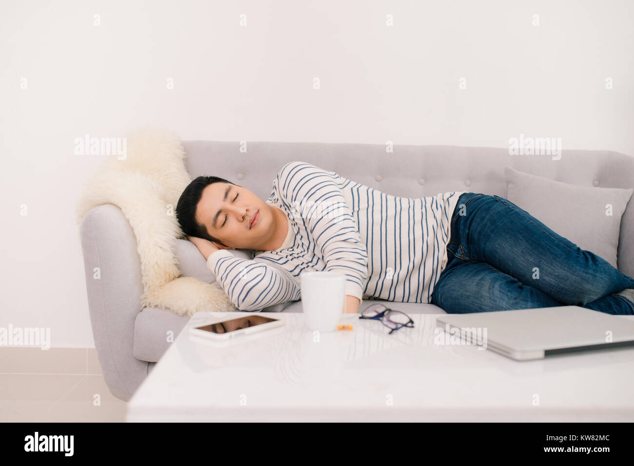 Young handsome asian man sleeping on sofa Stock Photo - Alamy
