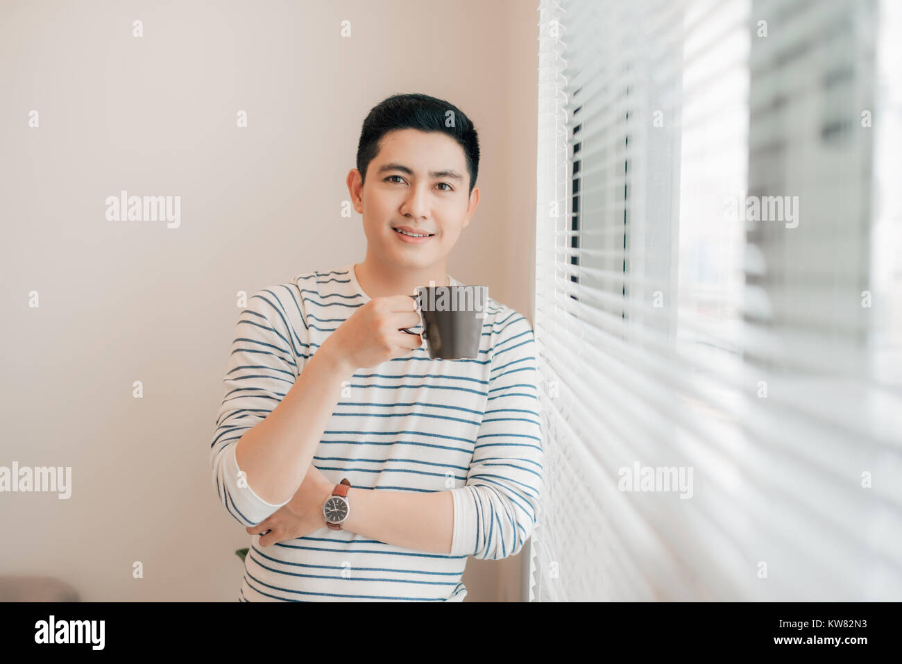 Man standing at window and drink first morning coffee Stock Photo - Alamy