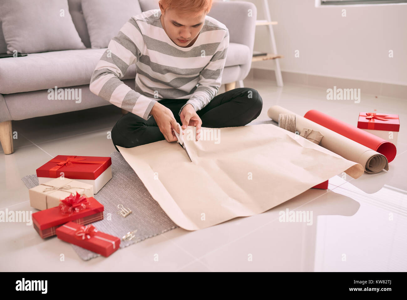 Young happy man packing Valentine gift while sitting on floor Stock ...