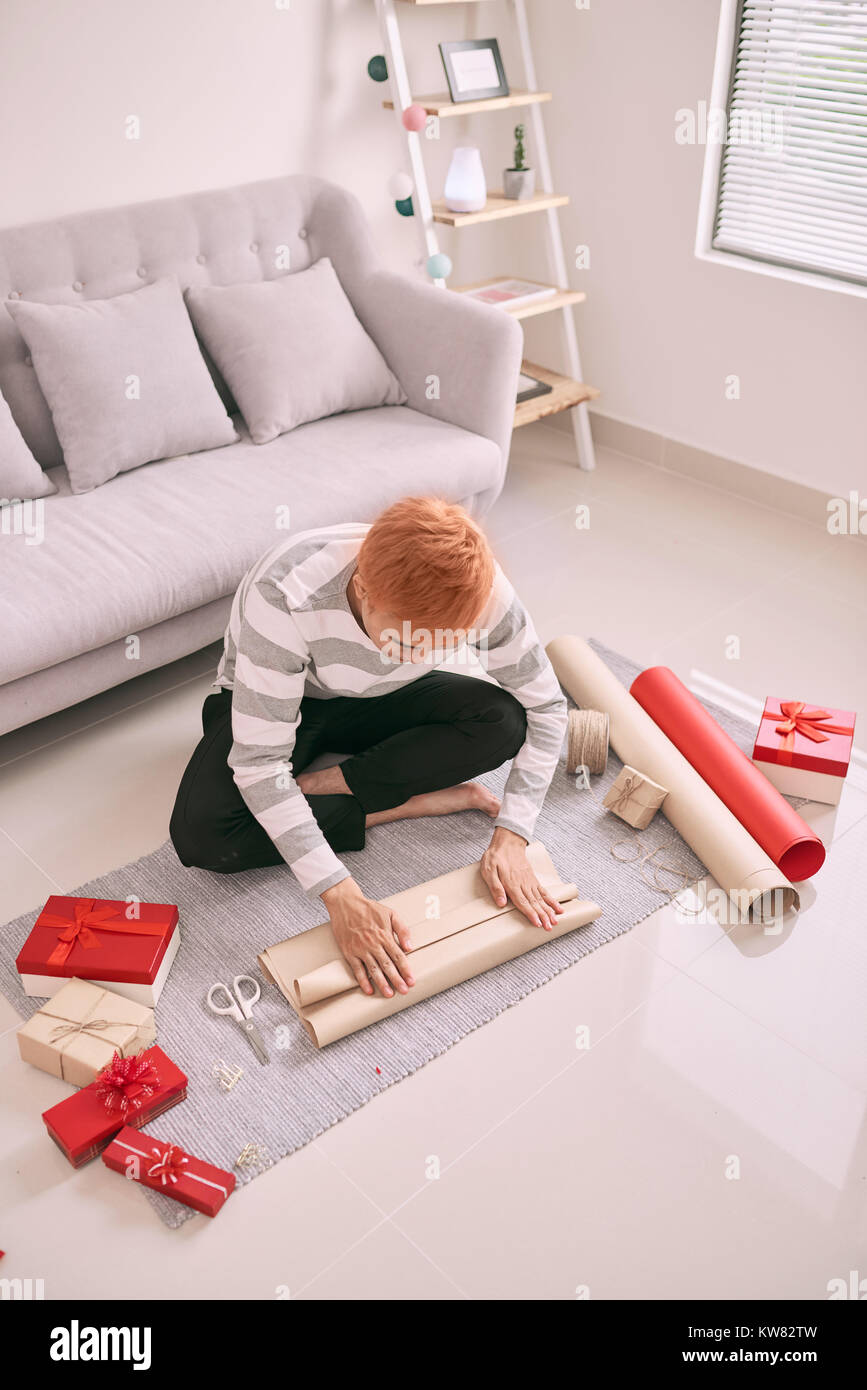 Young happy man packing Valentine gift while sitting on floor Stock ...