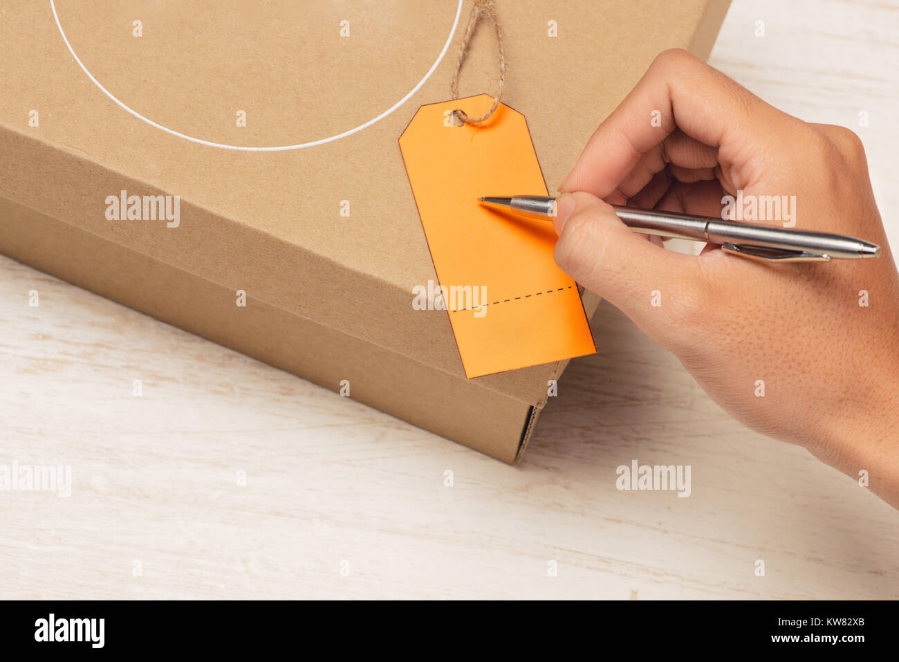 Male hand writing on luggage tag on brown paper parcel Stock Photo - Alamy