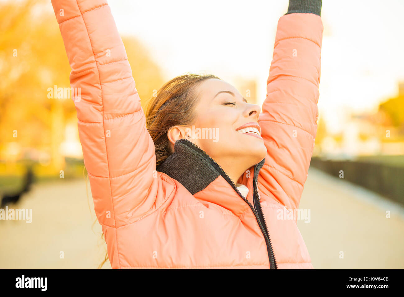 Young carefree woman holding hands up looking absolutely happy posing ...
