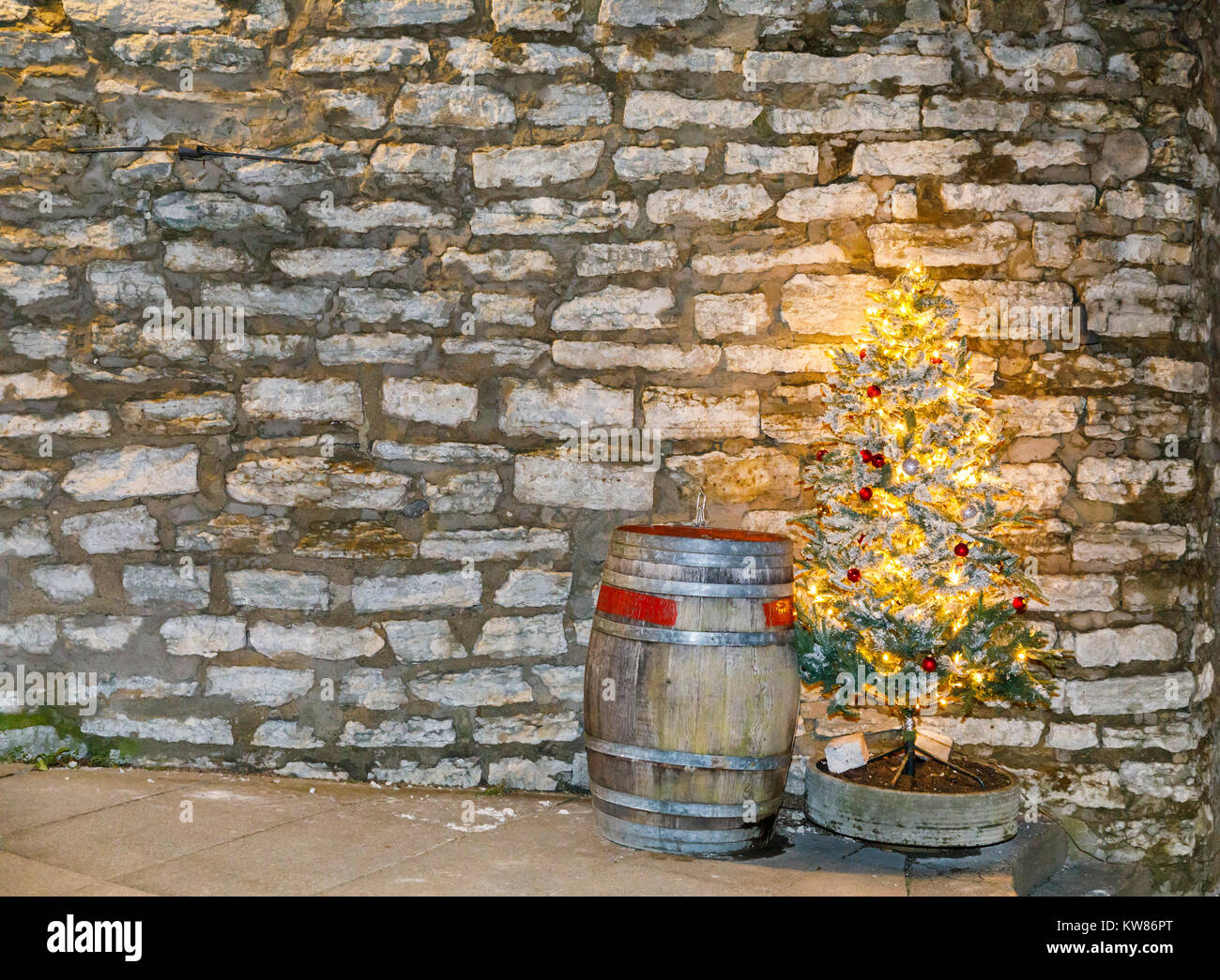 Old wooden barrel and illuminated christmas tree in front of limestone ...
