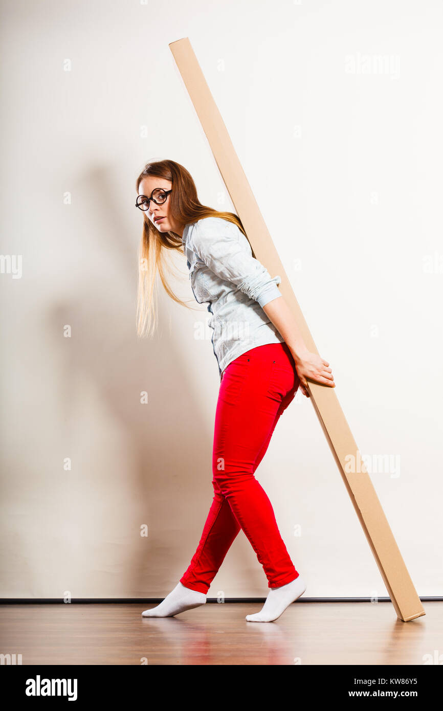 Woman moving into new apartment house carrying heavy carton box with ...