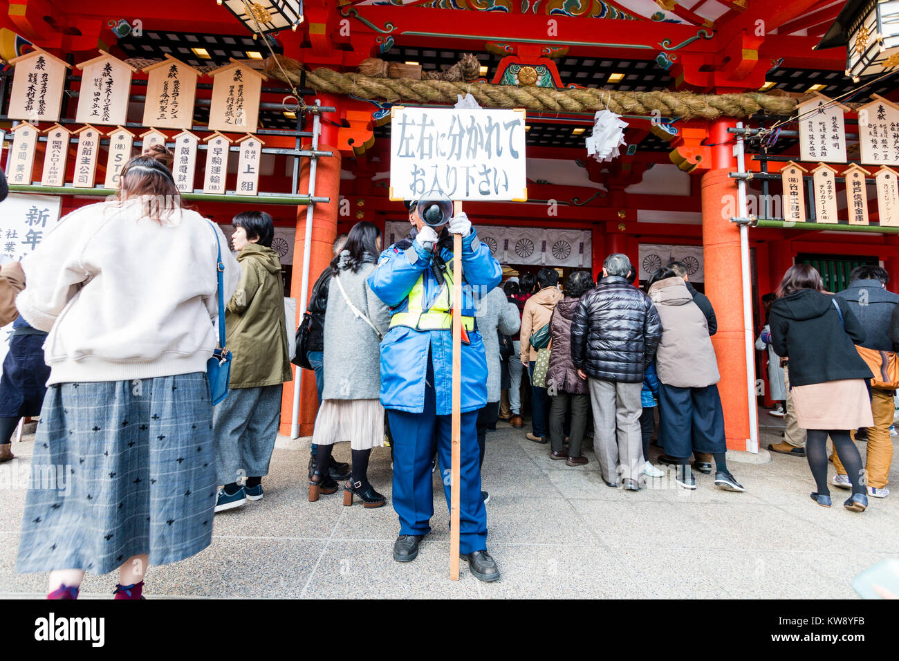 Japan, Kobe, Ikuta shrine. Security staff controlling crowds of people ...