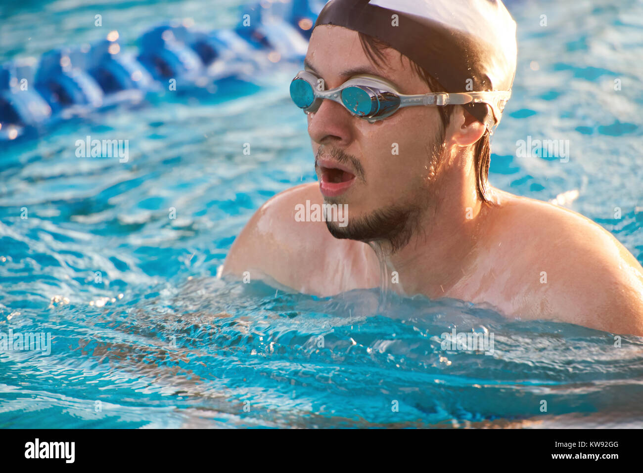 Man on swimming training in blue pool water close-up. Head of swimmer ...