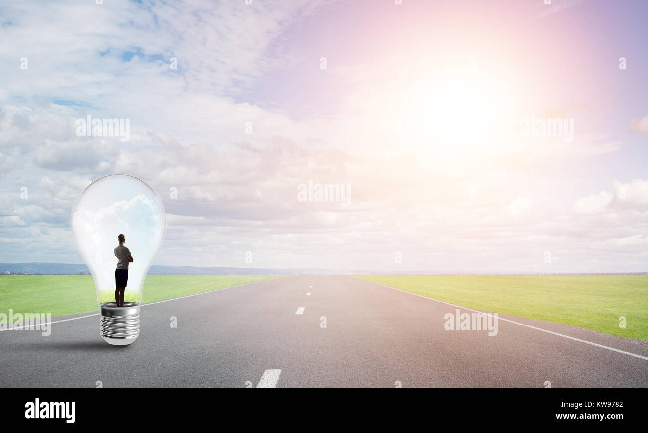 Young businesswoman trapped inside of light bulb on asphalt road Stock ...