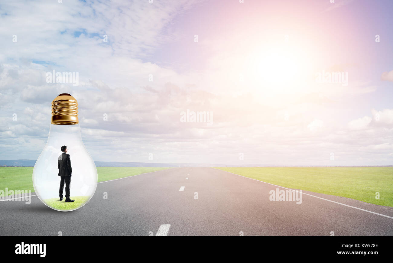 Young businessman trapped inside of light bulb on asphalt road Stock ...