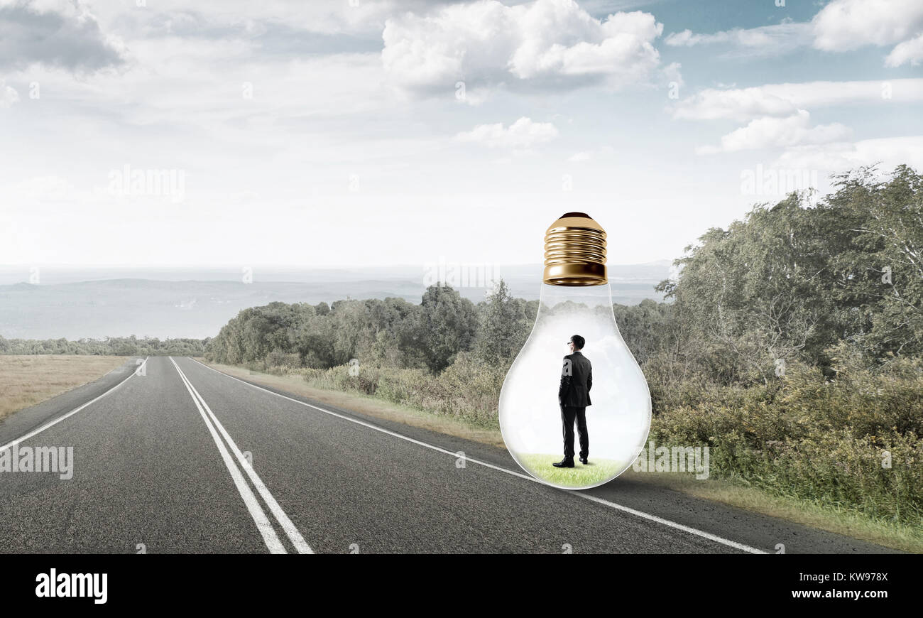Young businessman trapped inside of light bulb on asphalt road Stock ...