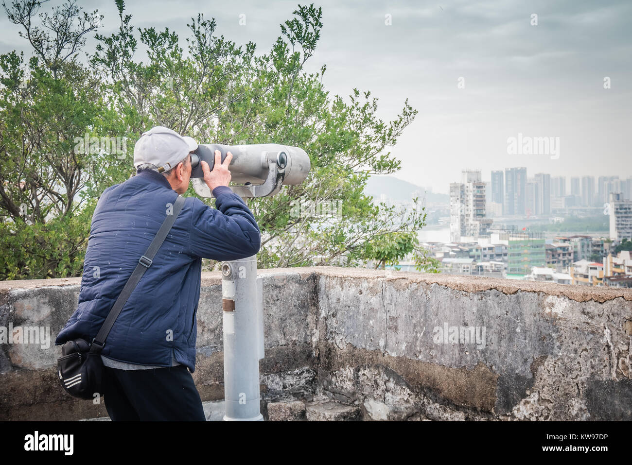 old man using the telescope in macau Stock Photo - Alamy