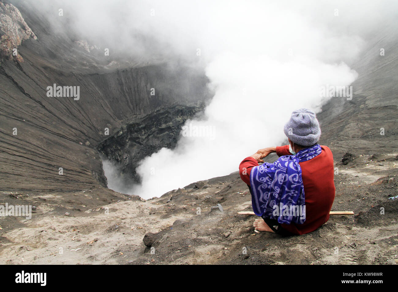 Man seated inside crater of volcano Bromo, Indonesian Stock Photo - Alamy