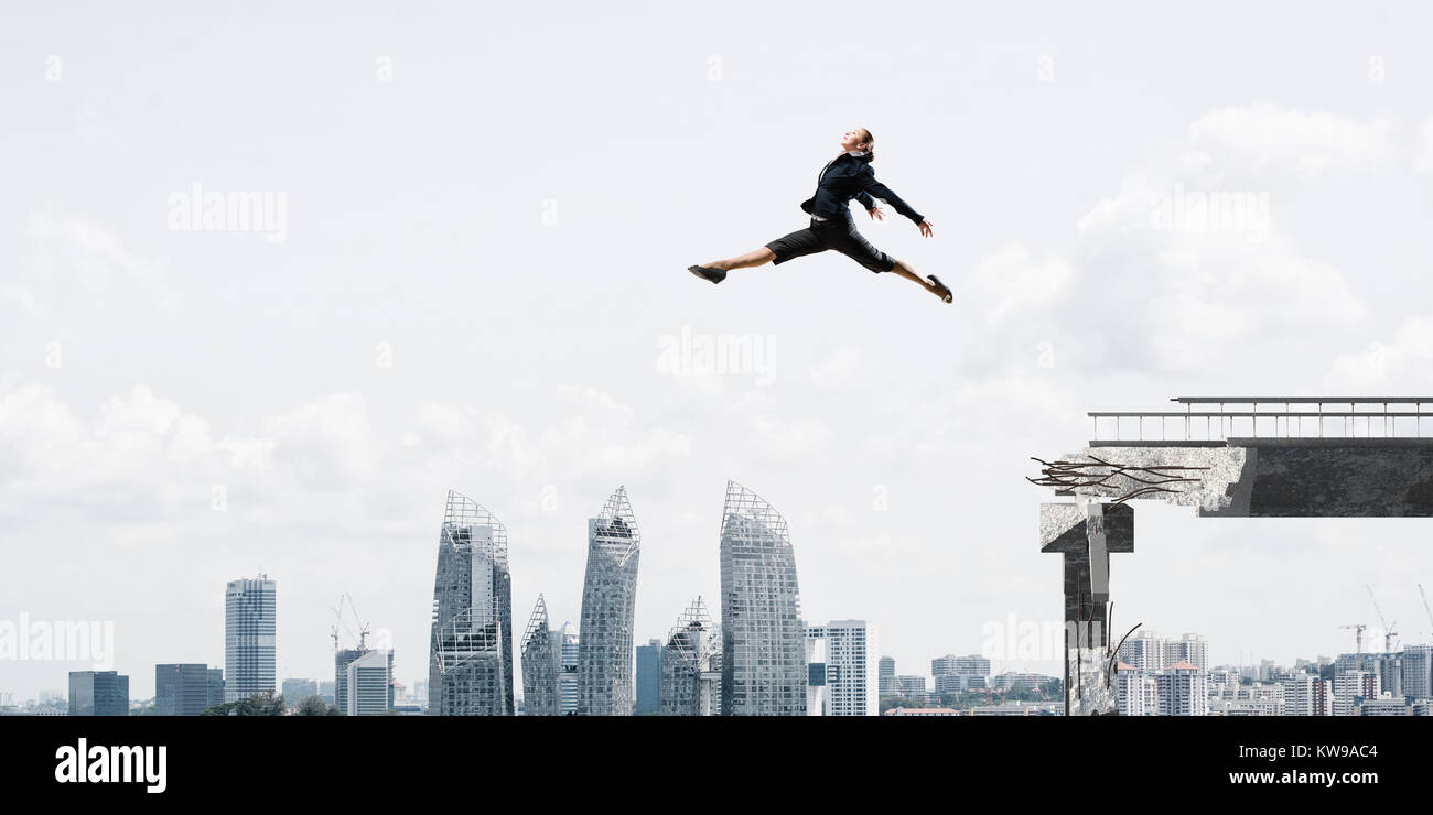 Business woman jumping over huge gap in concrete bridge as symbol of ...