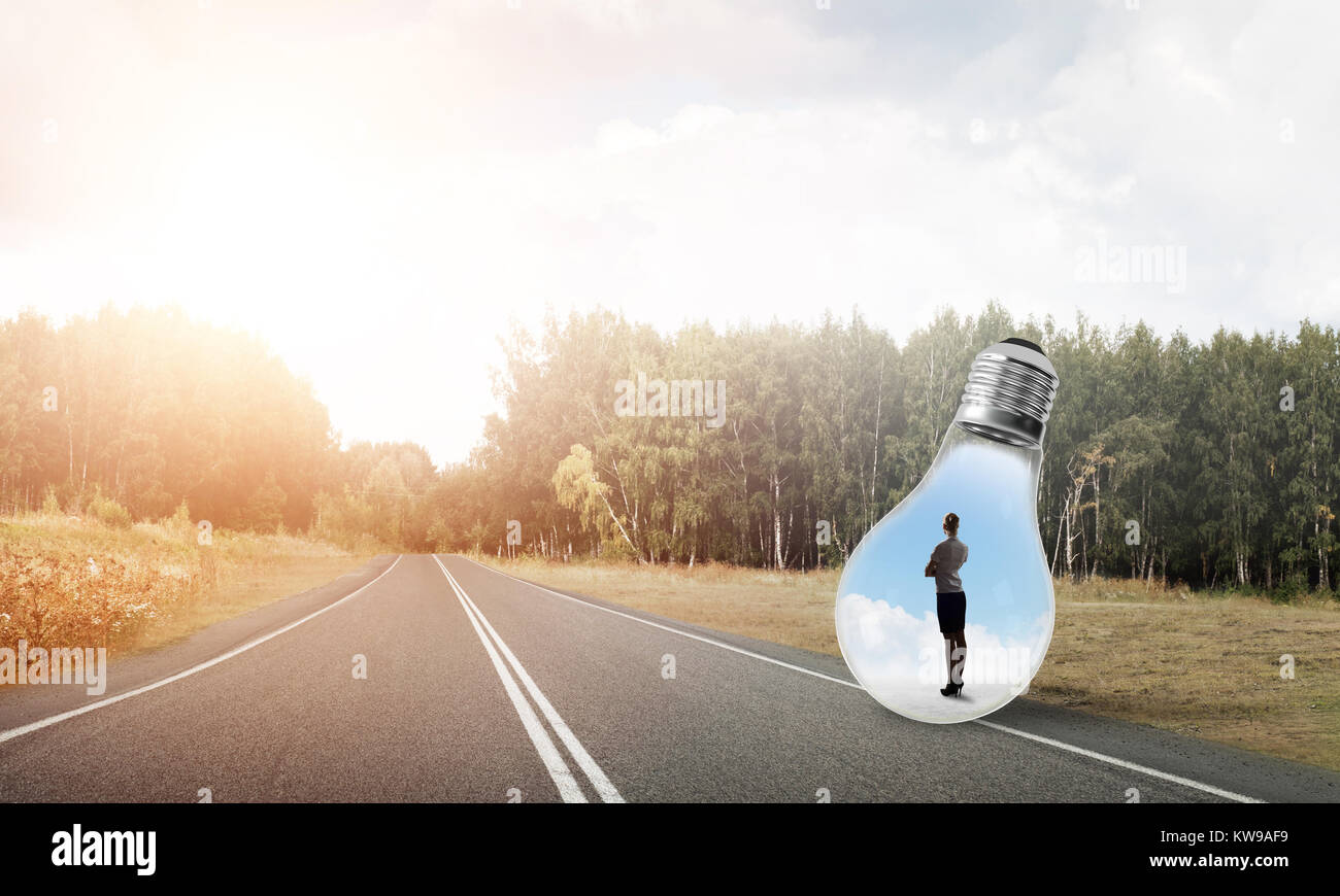 Young businesswoman trapped inside of light bulb on asphalt road Stock ...