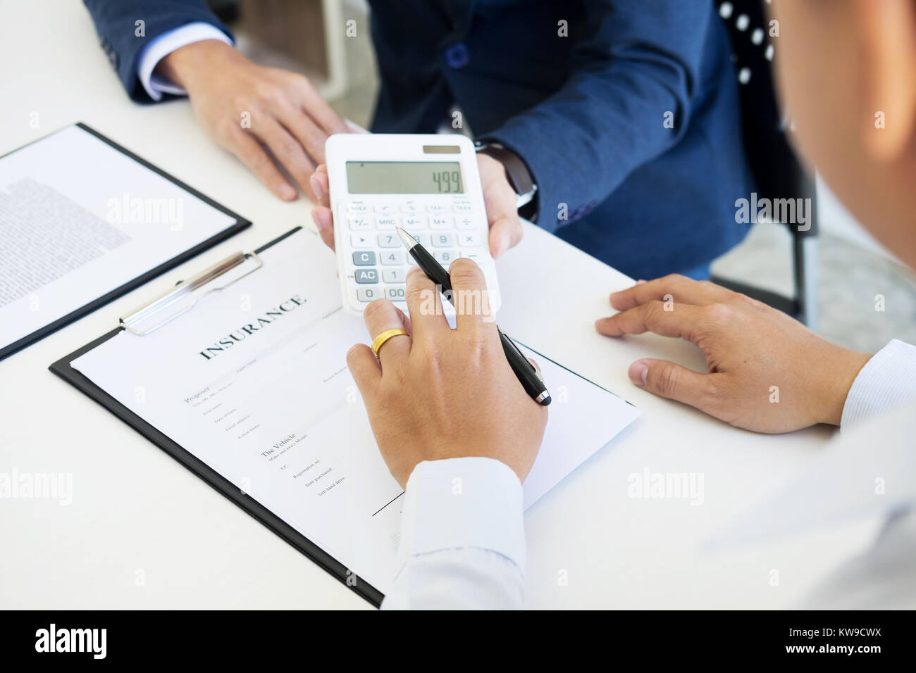 salesman holding a key and calculating a price at the dealership office ...
