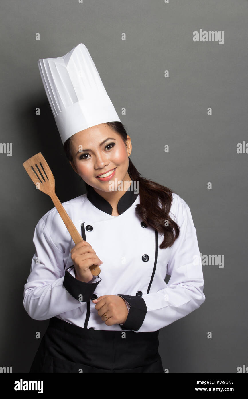 portrait of Pretty woman Chef in action, hold spatula over grey ...