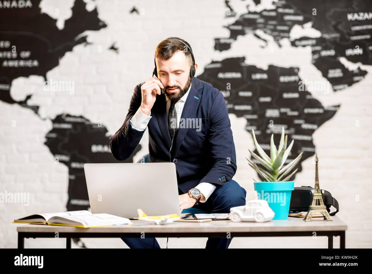 Handsome male agent working with laptop at the travel agency office ...
