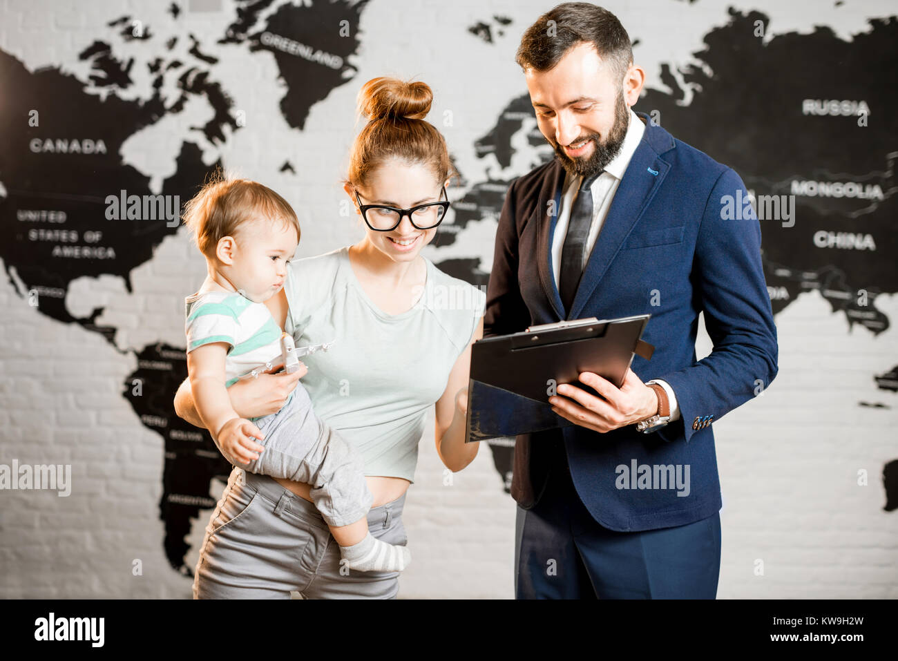 Happy mother and baby boy choosing tour for a summer vacation with male ...