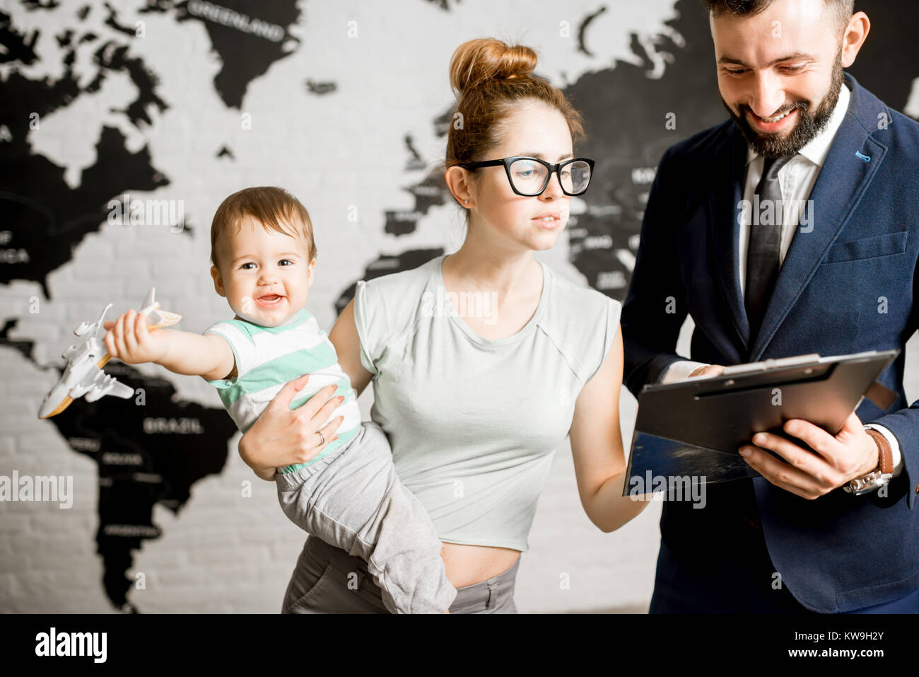 Happy mother and baby boy choosing tour for a summer vacation with male ...