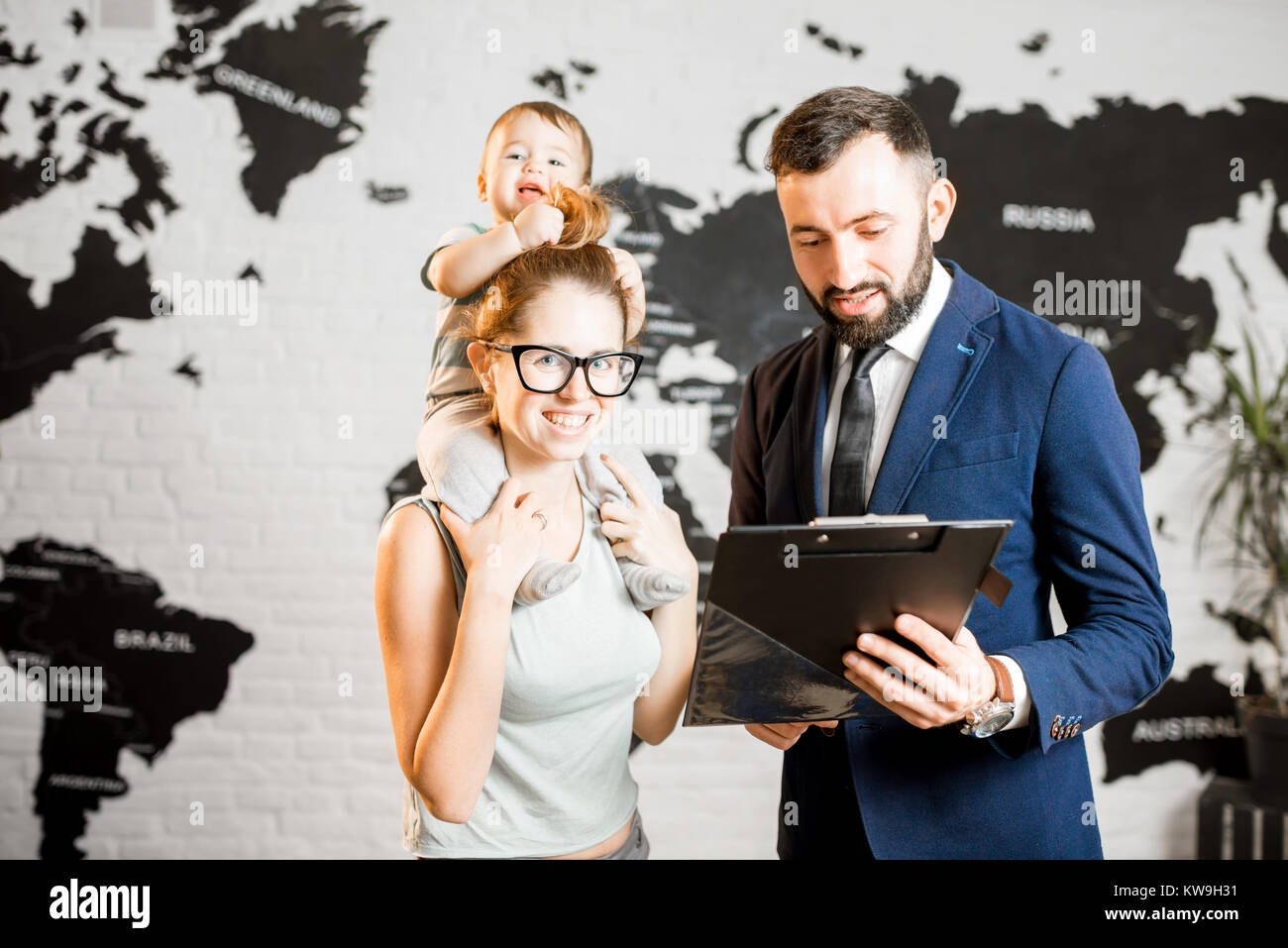 Happy mother and baby boy choosing tour for a summer vacation with male ...