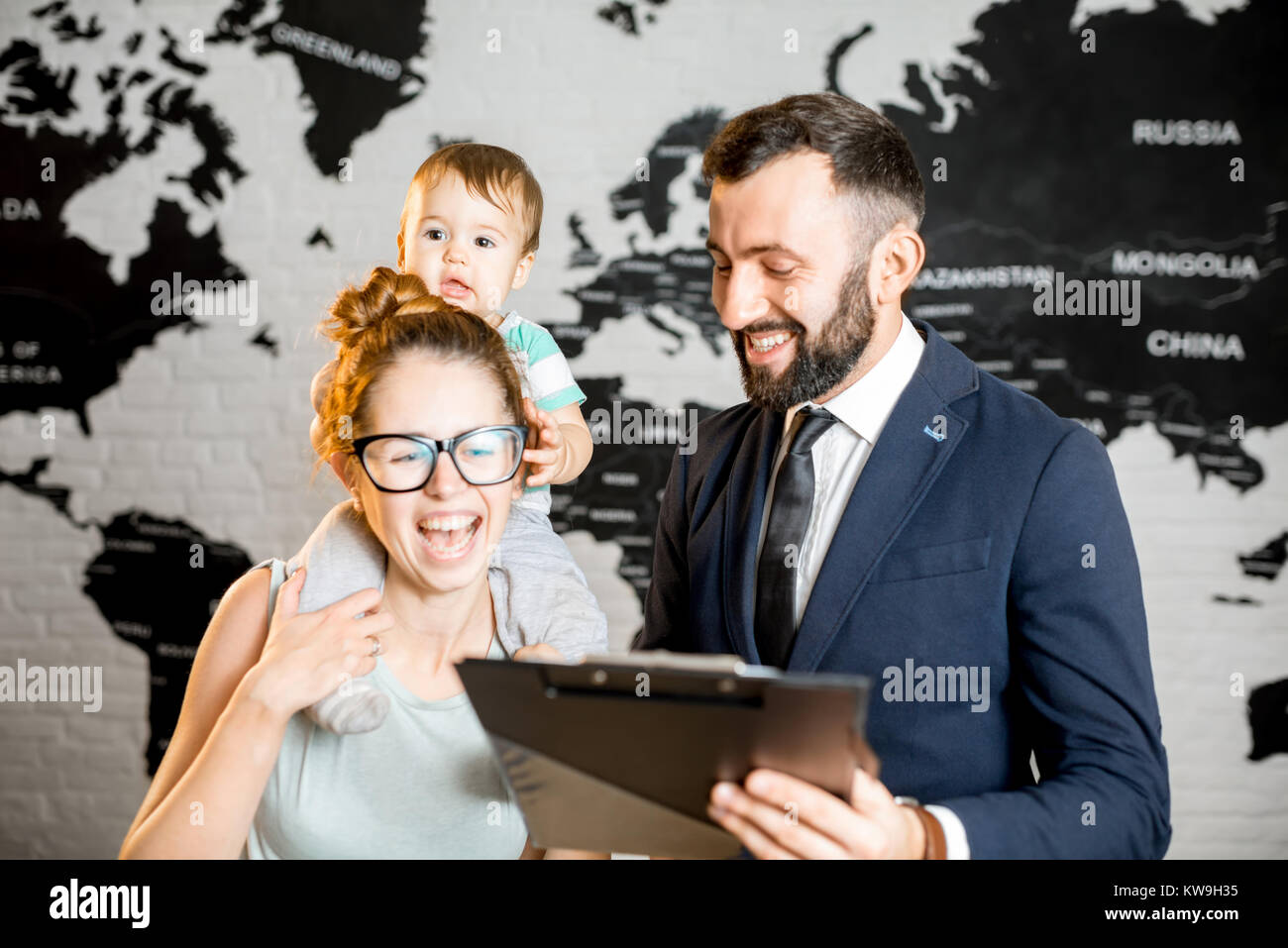 Happy mother and baby boy choosing tour for a summer vacation with male ...