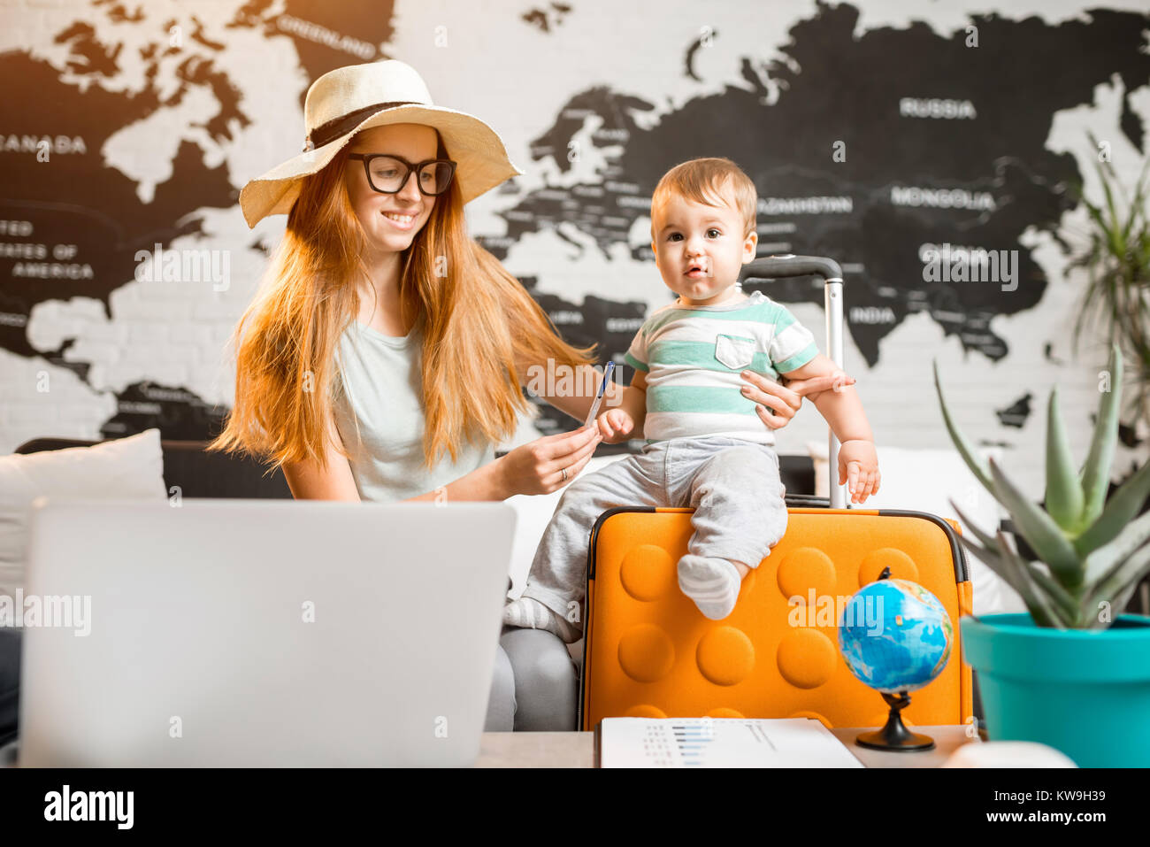 Happy and playful woman with baby boy sitting at the travel agency ...