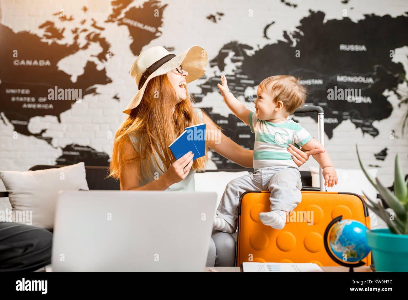 Happy and playful woman with baby boy sitting at the travel agency ...