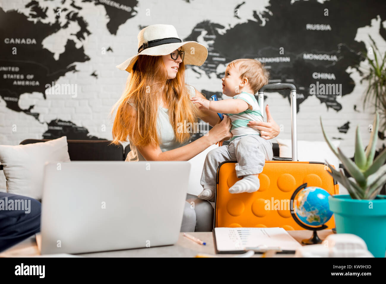 Happy and playful woman with baby boy sitting at the travel agency ...