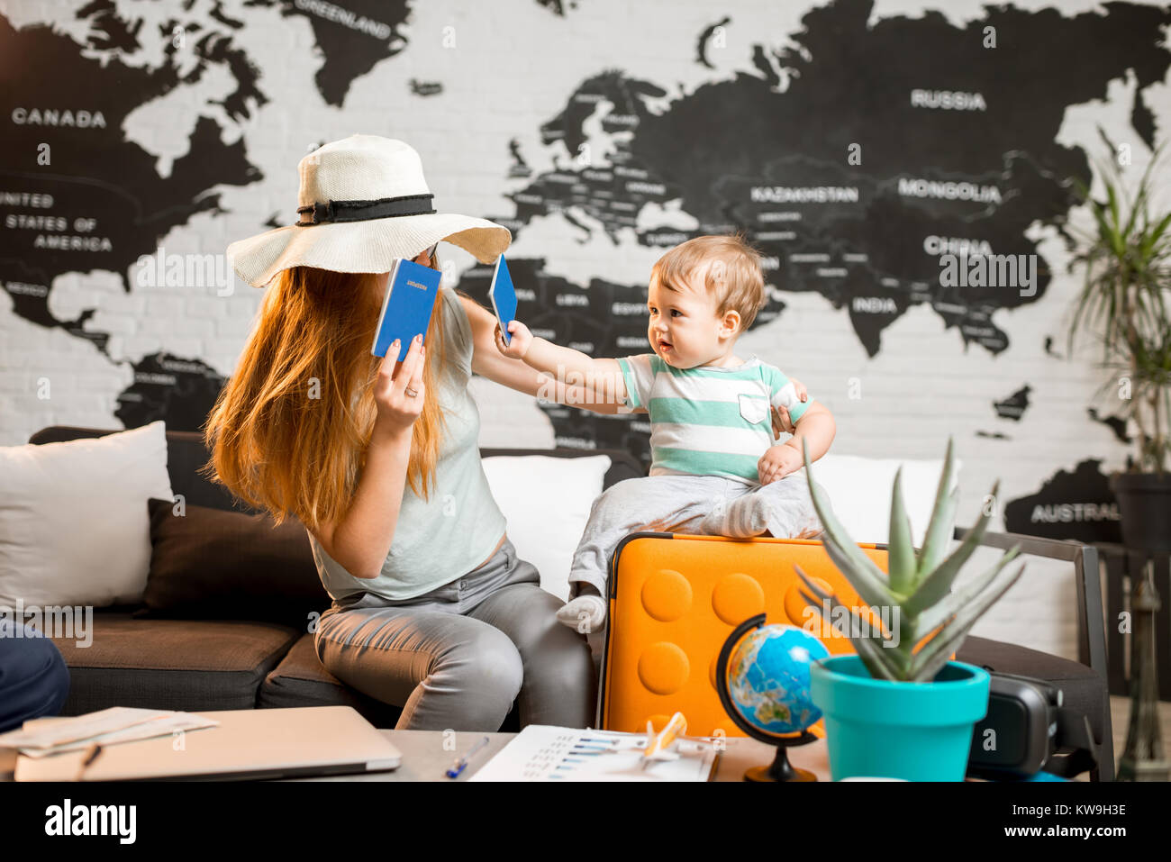 Happy and playful woman with baby boy sitting at the travel agency ...
