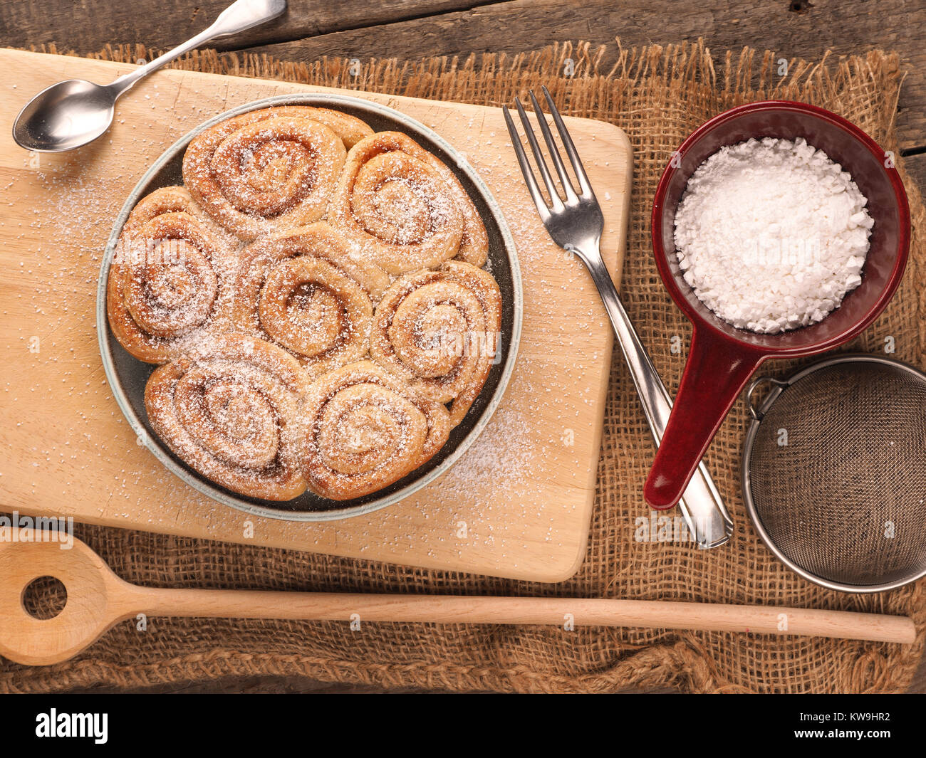 Homemade cinnamon snails with kitchen utensils on a rustic wooden ...