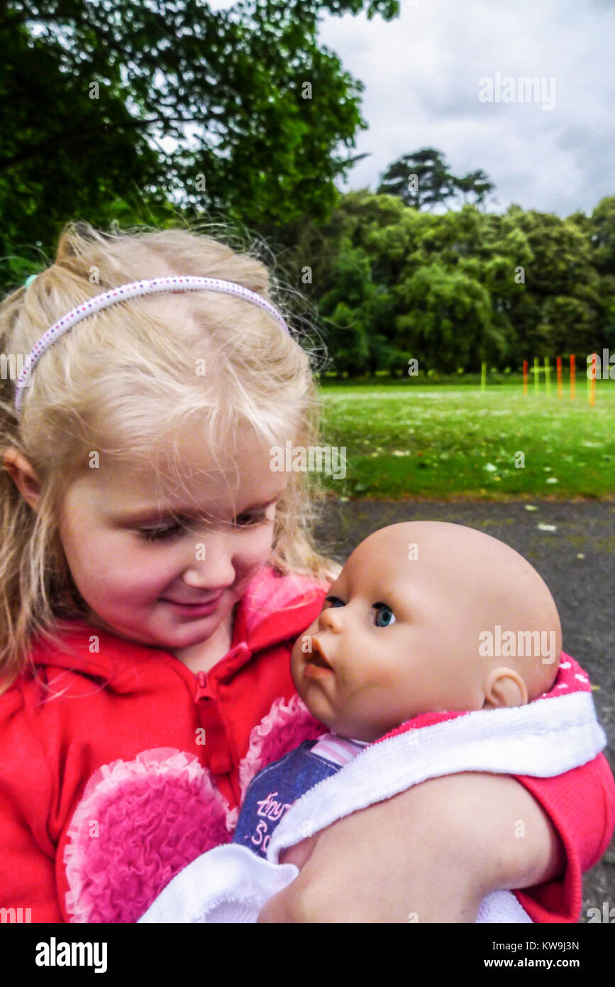 Closeup of little girl, child looking at her doll with love, joy ...