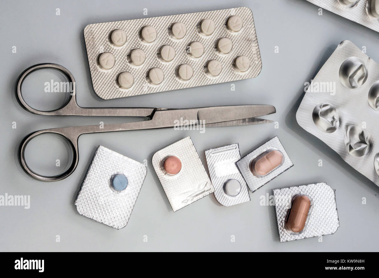 Scissors next to several blister cut, conceptual image Stock Photo - Alamy