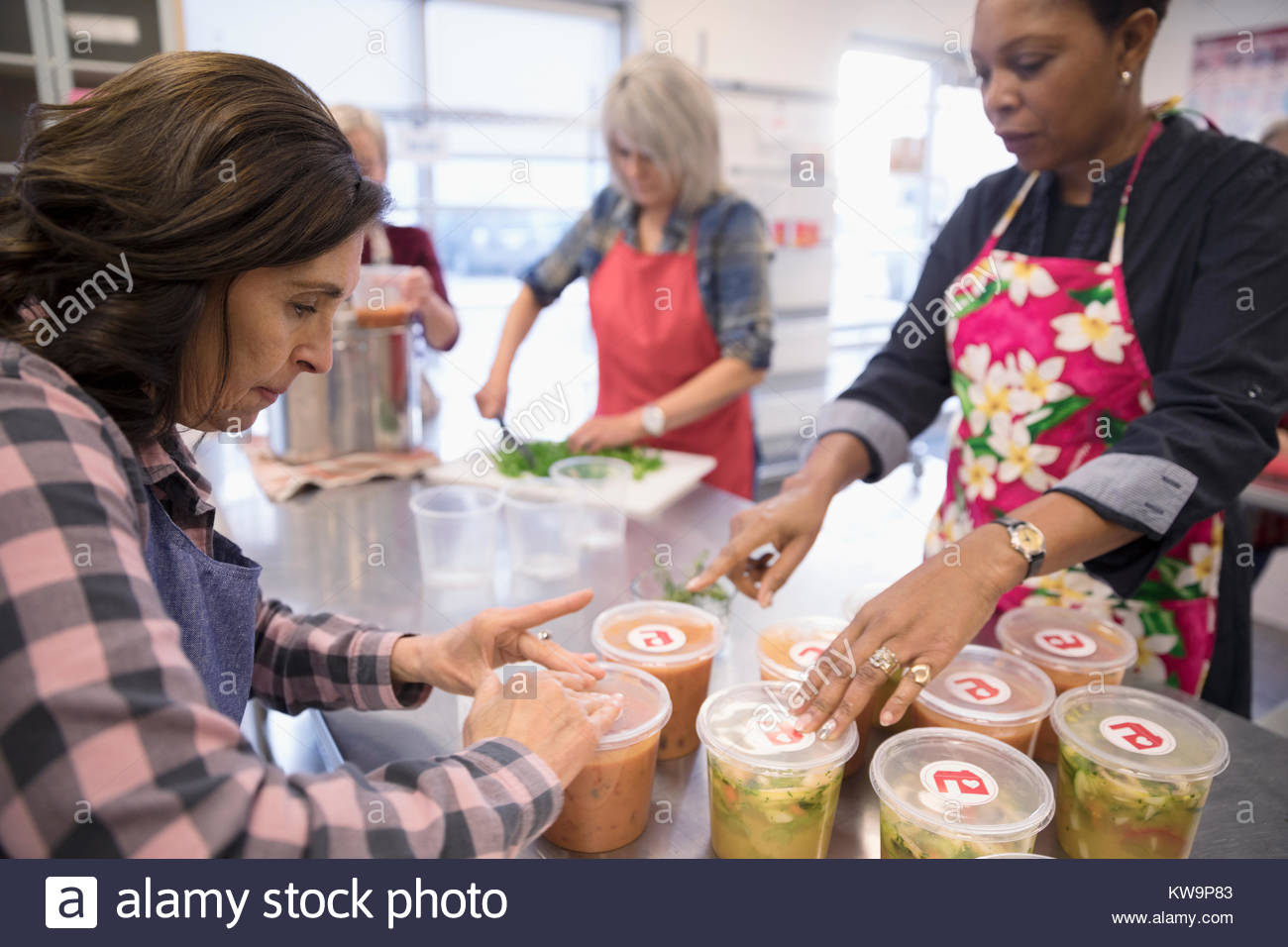 Female volunteers packaging soup containers in soup kitchen Stock Photo ...