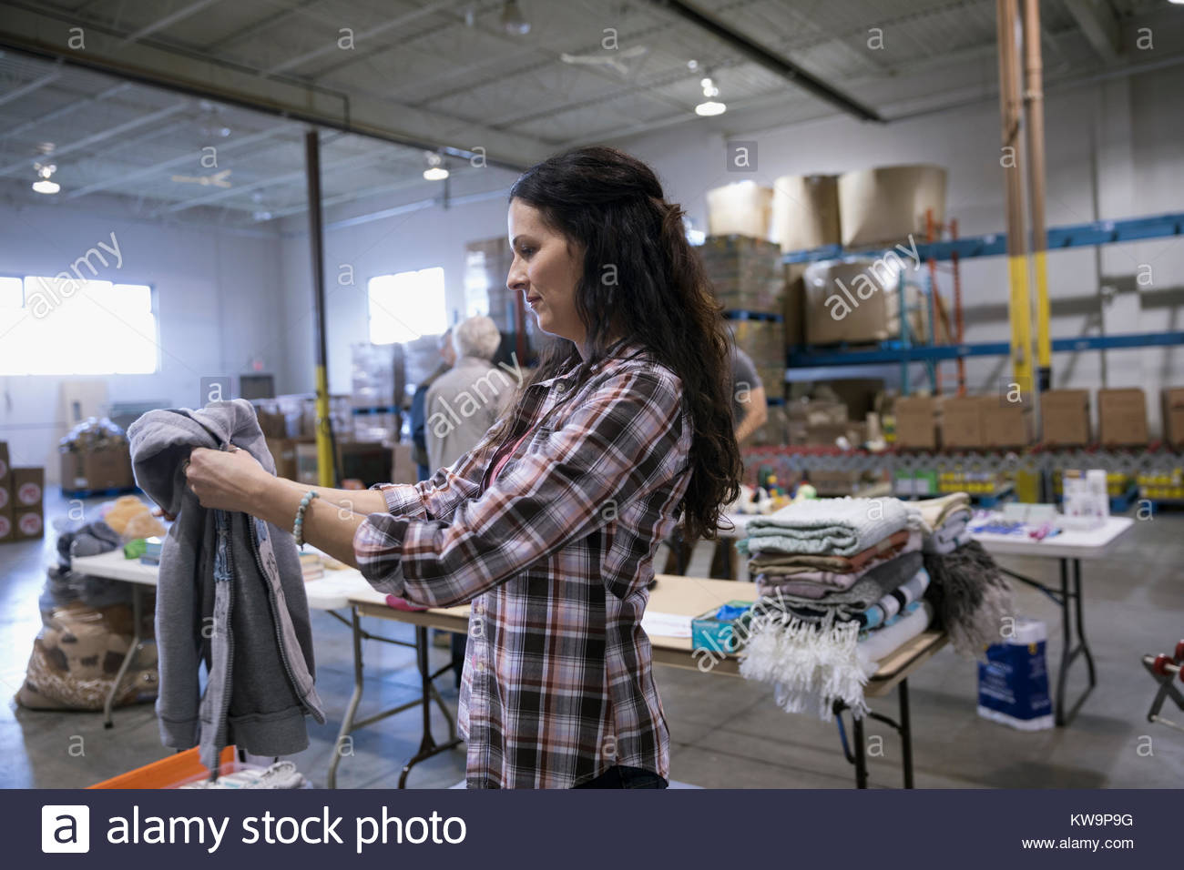 Female volunteer sorting clothing for clothing drive in warehouse Stock ...