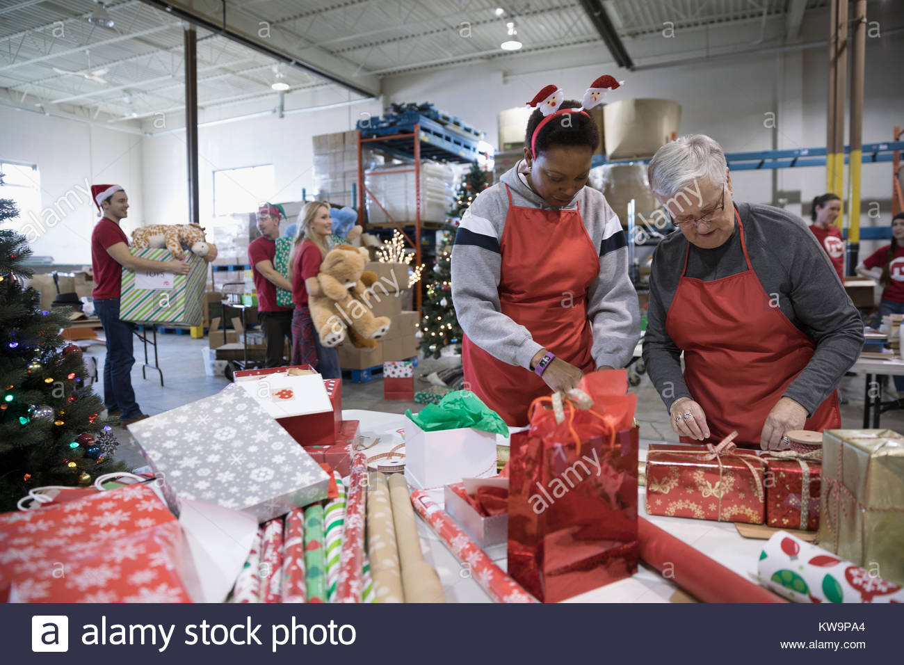 Smiling female volunteers wrapping Christmas gifts in warehouse Stock ...