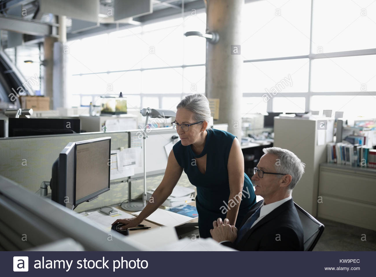 Businessman and businesswoman meeting,using computers in office cubicle ...