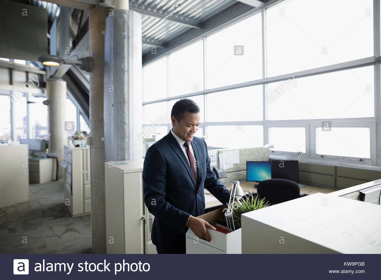 Businessman being laid off,holding box of belongings at office cubicle ...