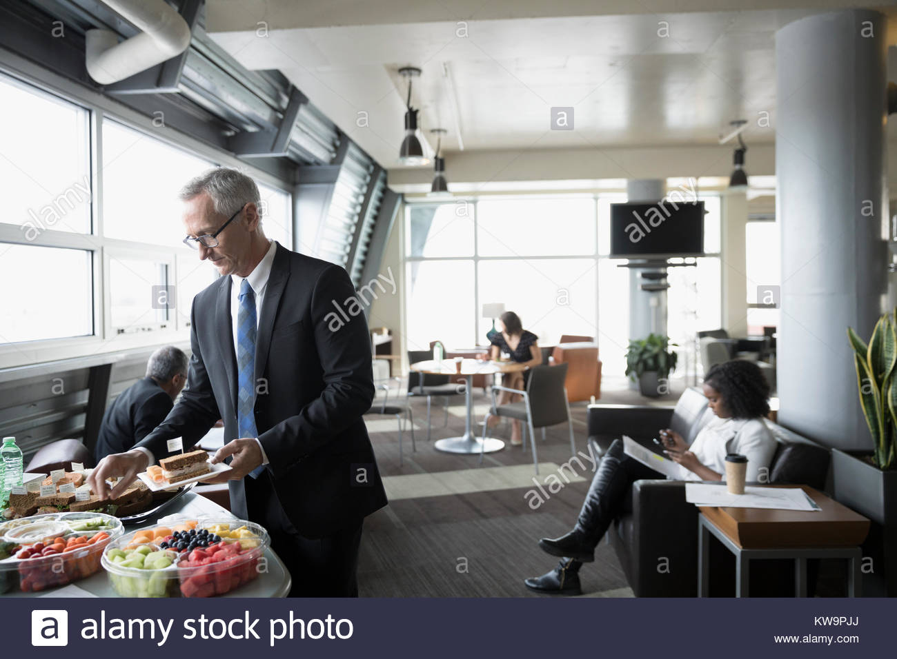 Businessman eating at buffet in business lounge Stock Photo - Alamy