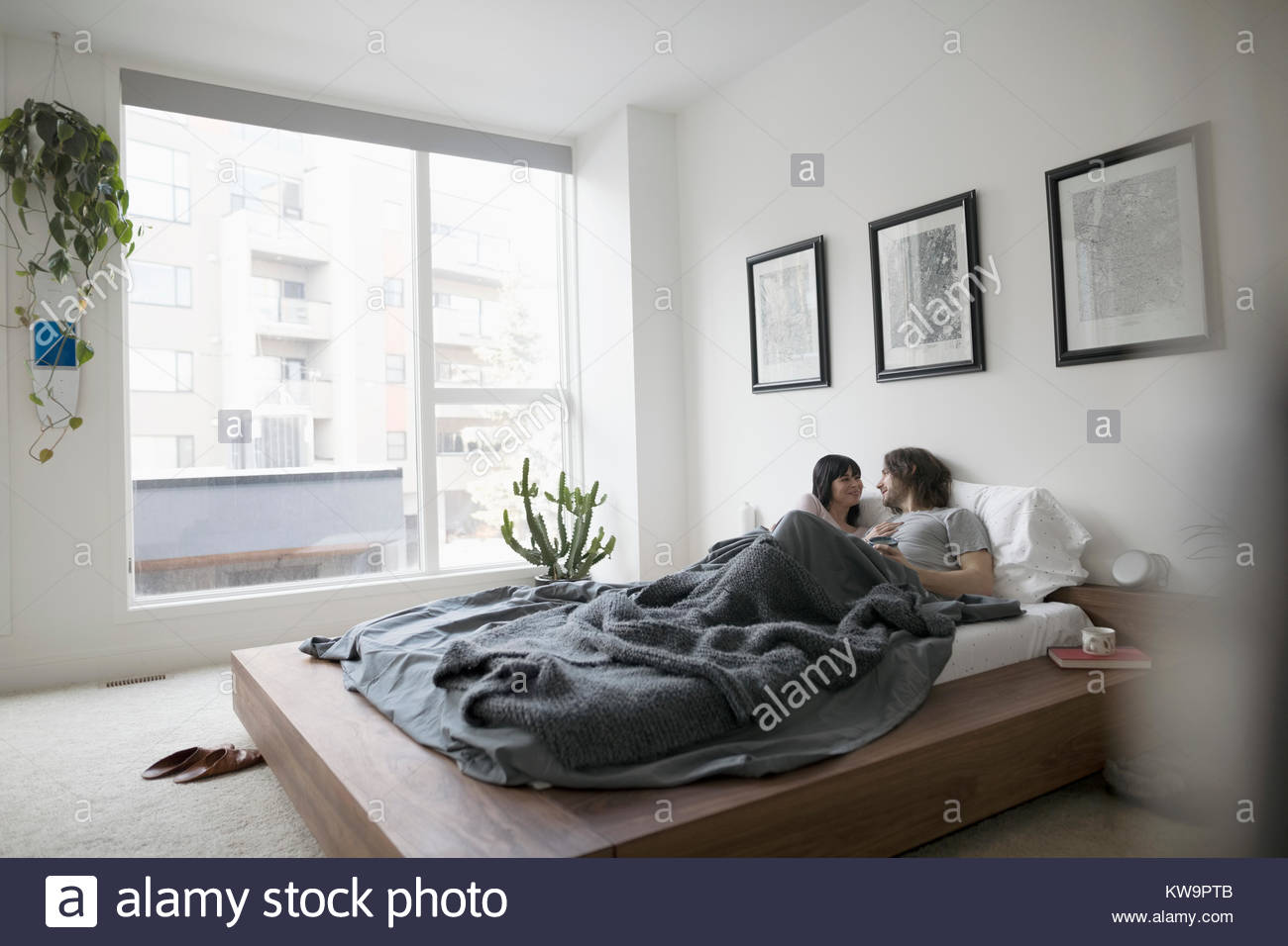 Affectionate couple cuddling in bed in urban apartment bedroom Stock ...