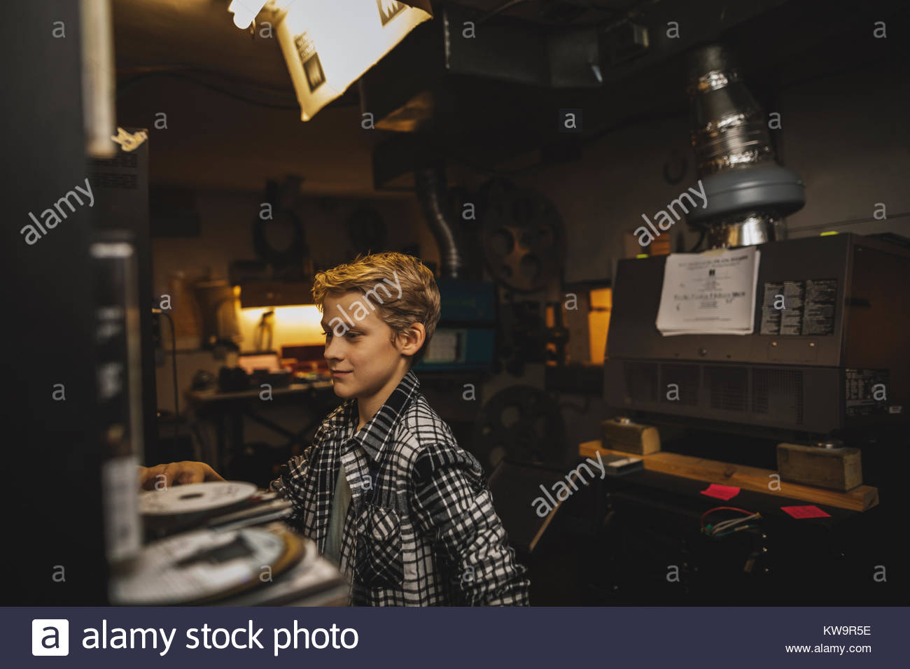 Caucasian tween boy projectionist operating equipment in movie theater ...