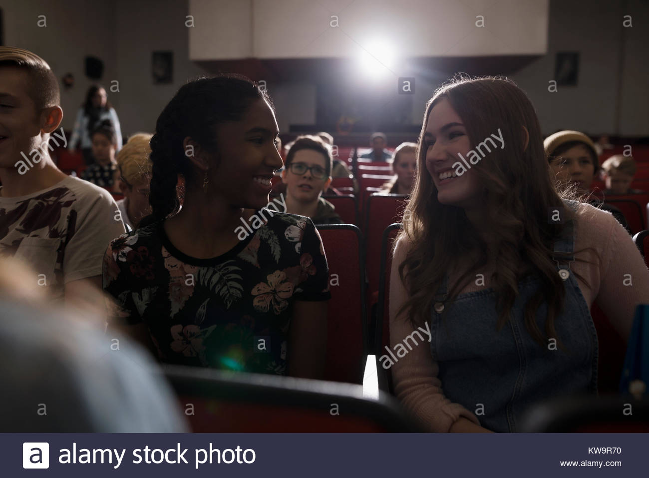 Smiling tween girl friends watching movie in dark movie theater Stock ...