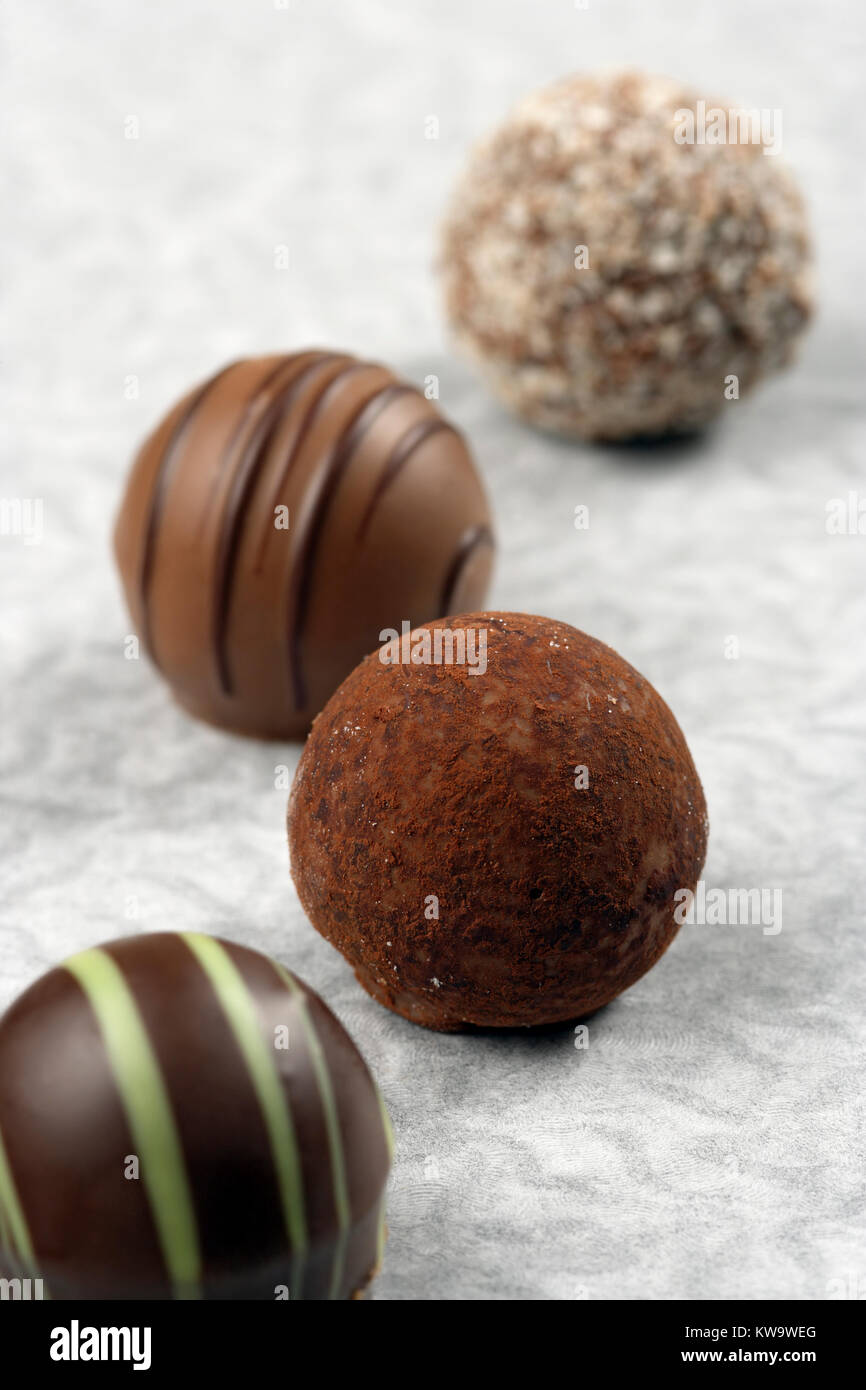 Photo of a small assortment of chocolate truffles and pralines on paper ...