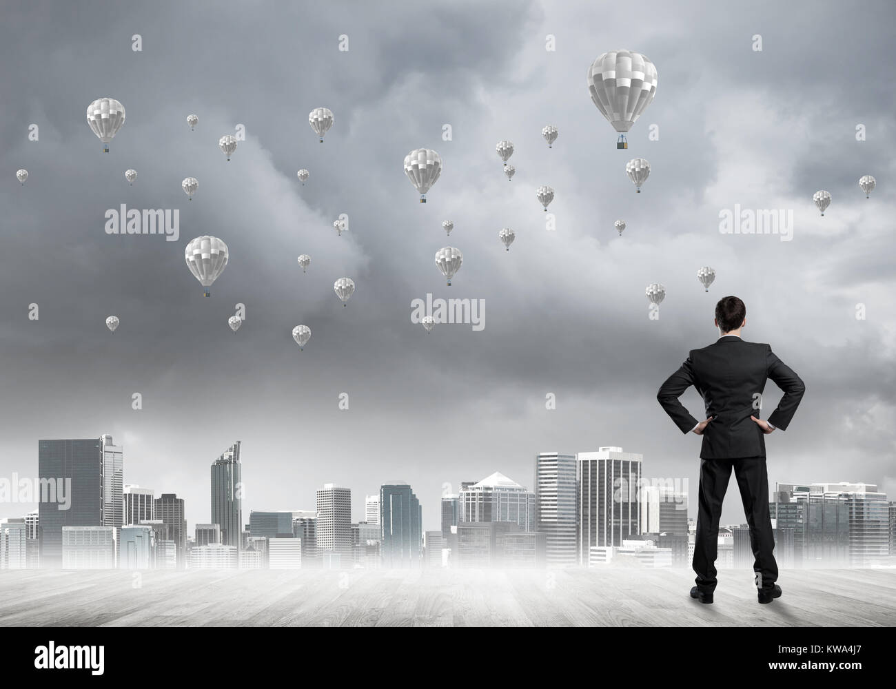 Businessman standing with back and looking at aerostats flying in air ...