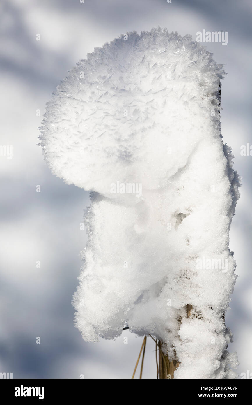 Glittering ice structures on a pile of snow on a pole after a freezing ...